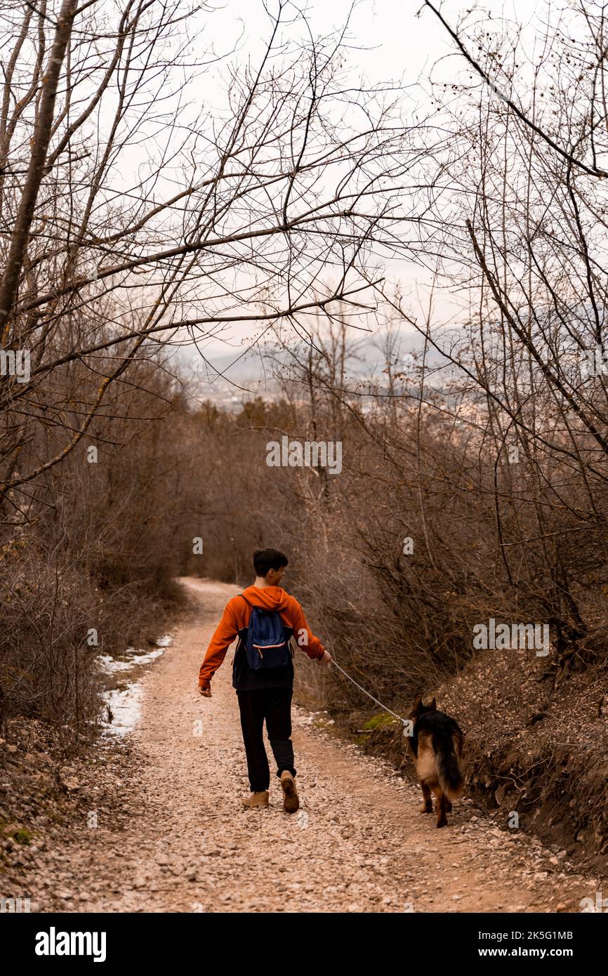 Handsome and amazing guy is walking the dog alone on the forest path ...