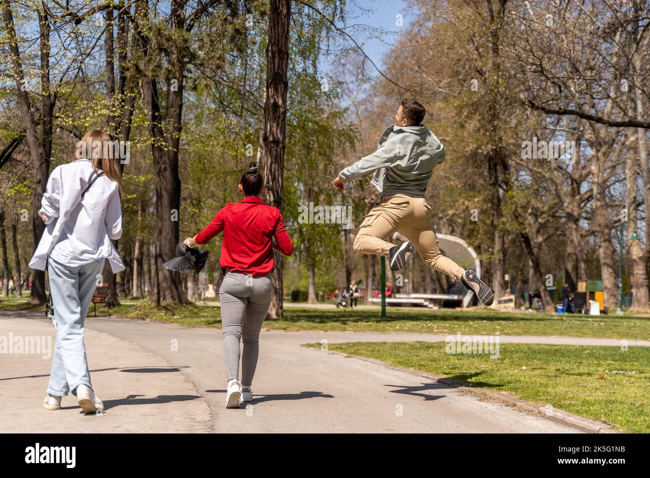 Full body happy women and man in casual outfits walking in summer park ...