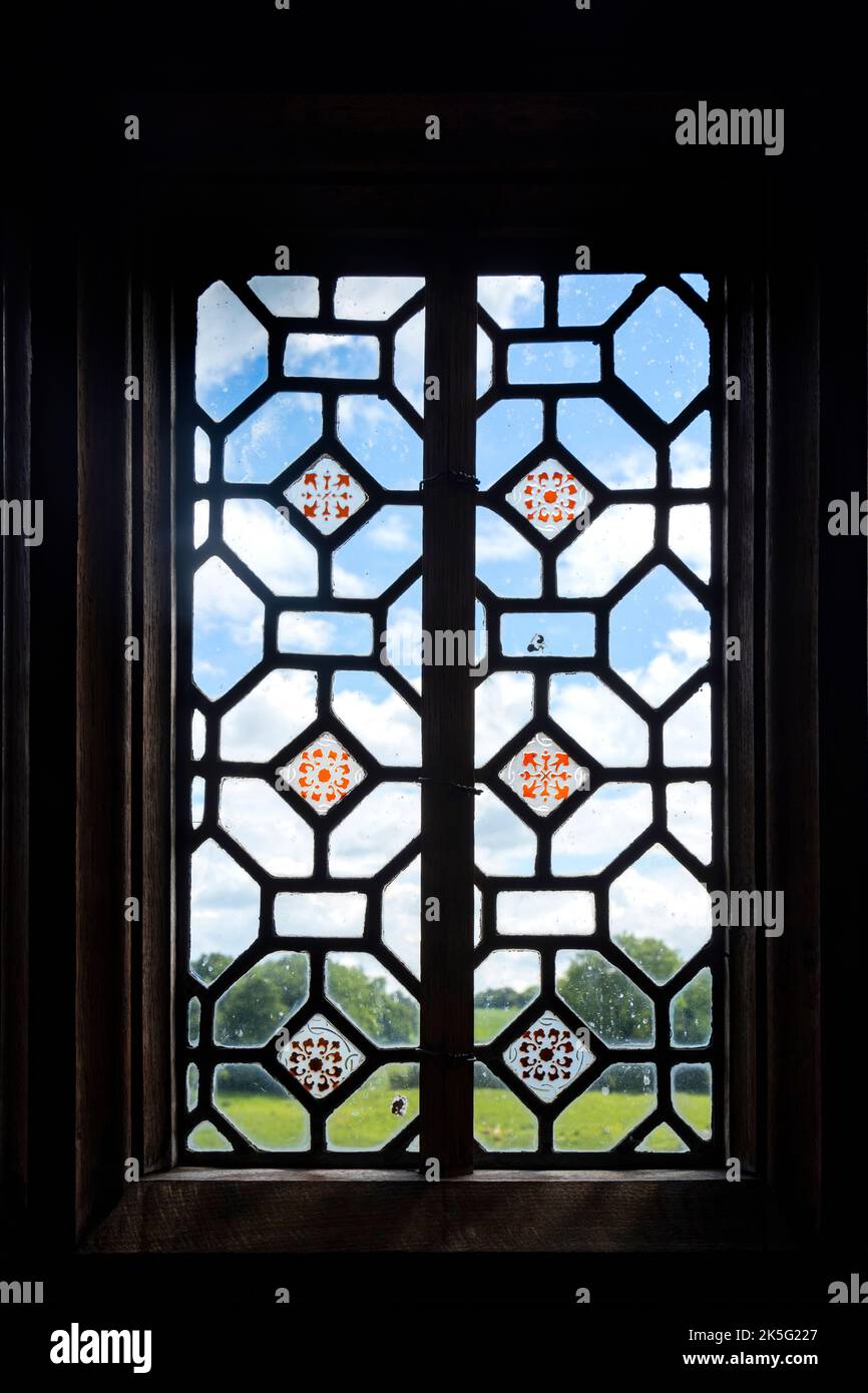 stained glass window of Tudor half timbered moated National Trust house ...