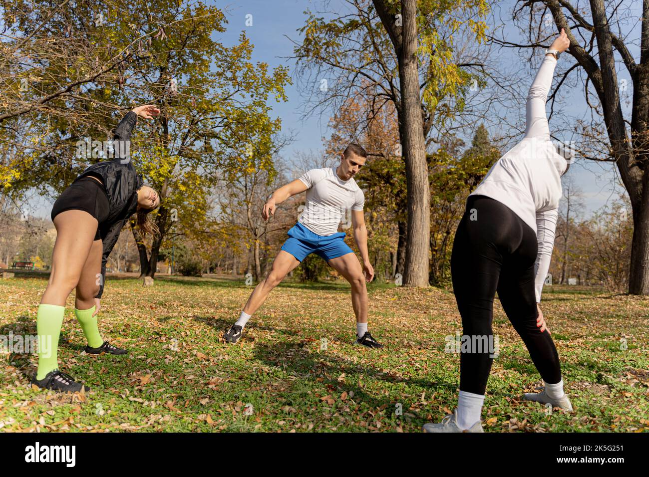 Three attractive and amazing fit friends are warming up and stretching ...