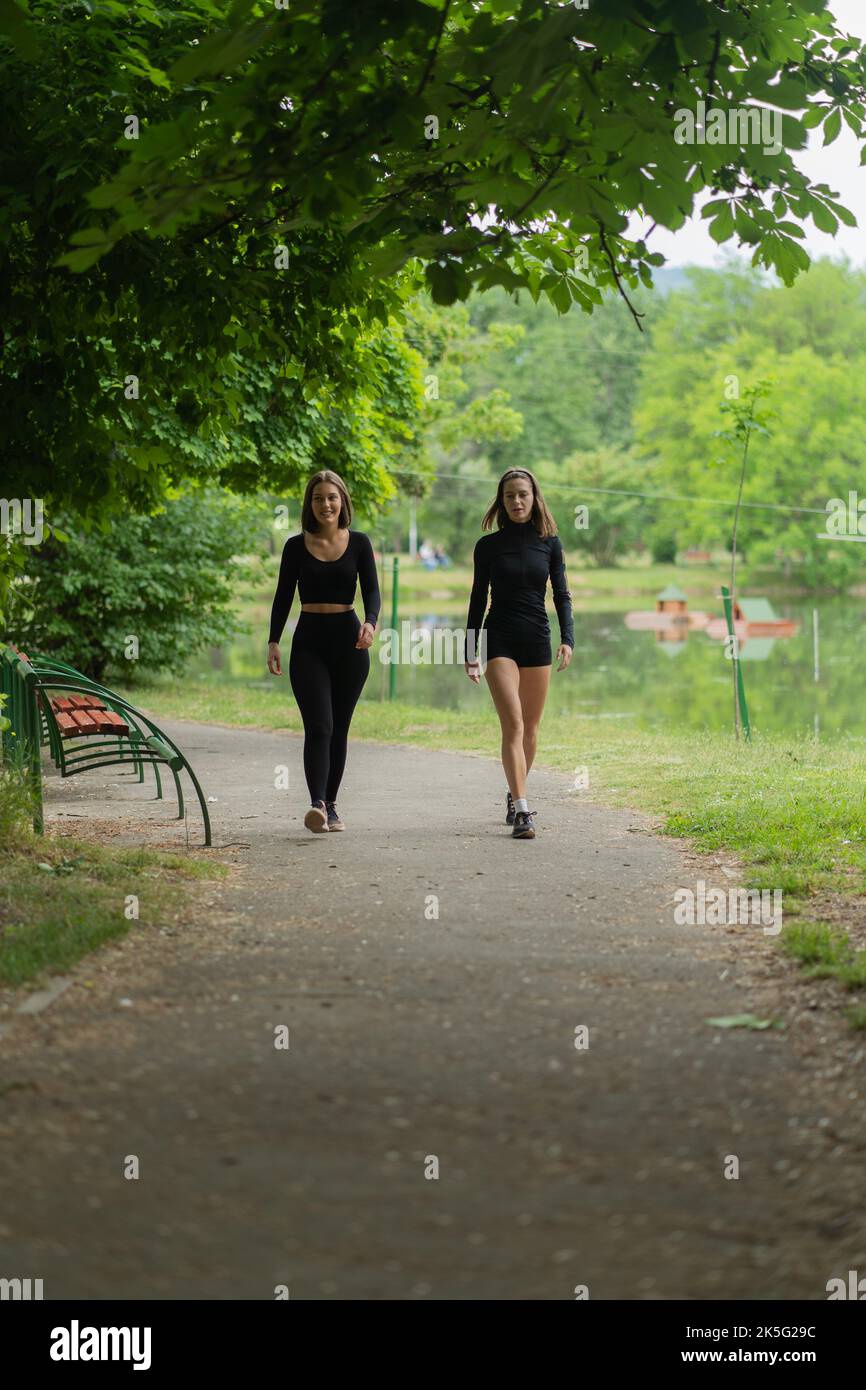Two attractive and beautiful girls are walking together and talking ...