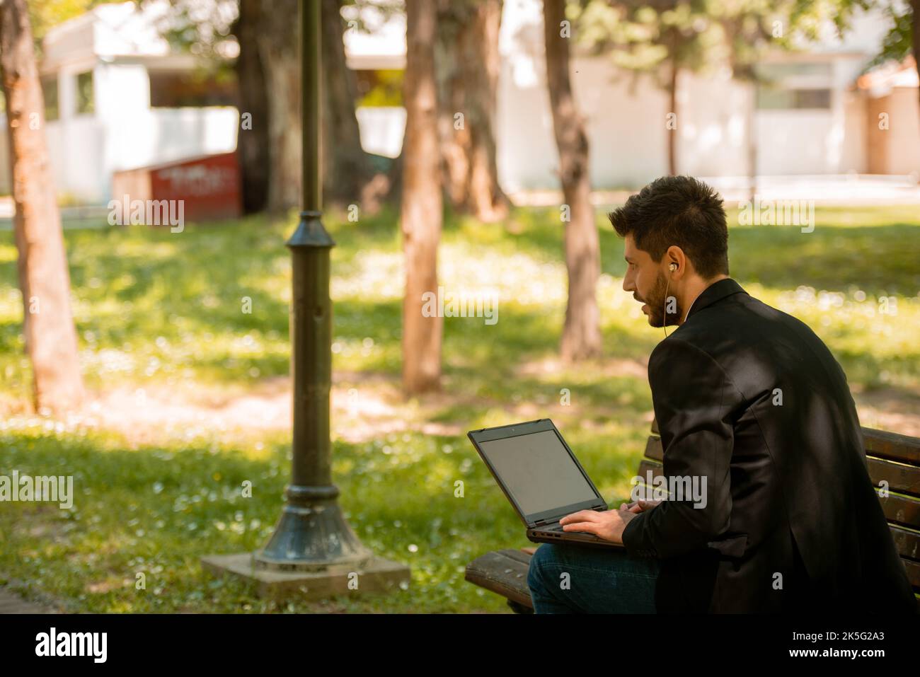Businessman on a video call sitting on the bench in the park Stock ...