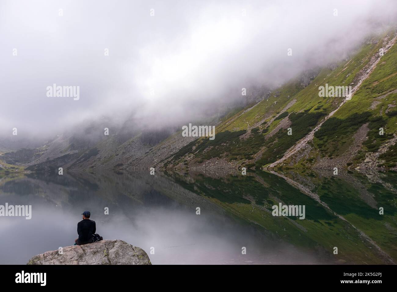 Peaceful landscape in the Polish Tatra Mountains with a lake and a man ...
