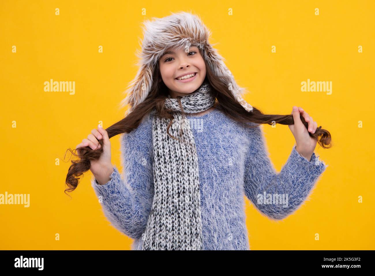 Modern teen girl wearing sweater and knitted hat on isolated yellow ...