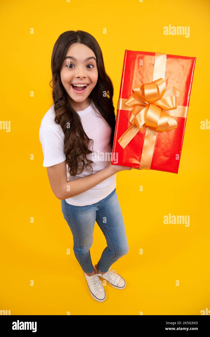 Amazed teenager. Child with gift present box on isolated studio ...