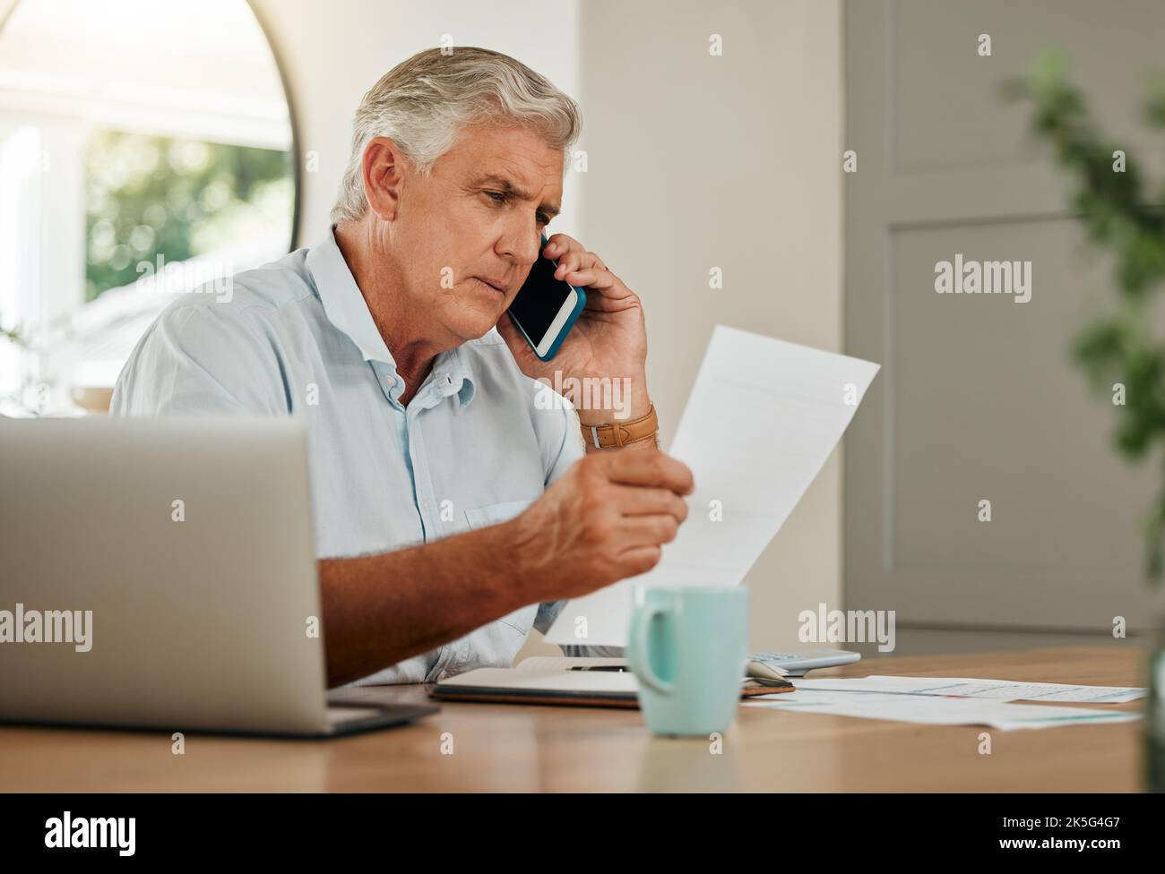 Senior man on a phone call with finance documents for debt counselling ...