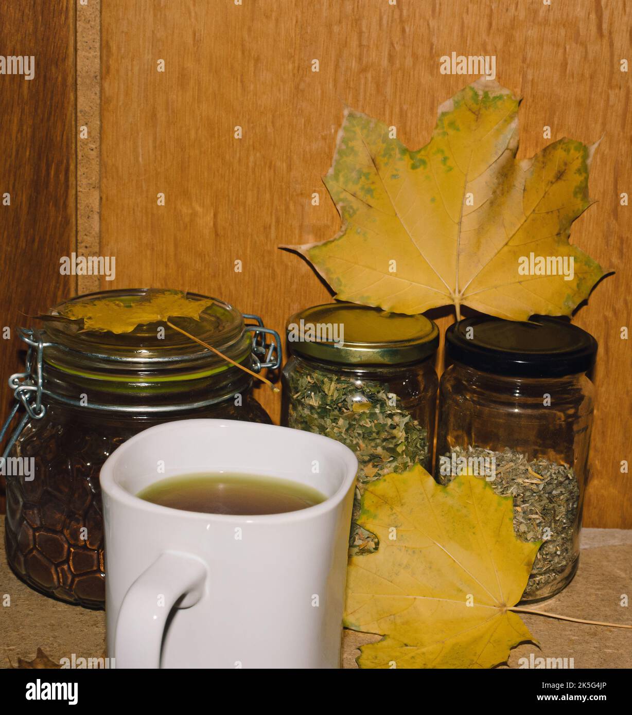 Glass bottles with ground coffee and teas with yellow leaves. On the ...