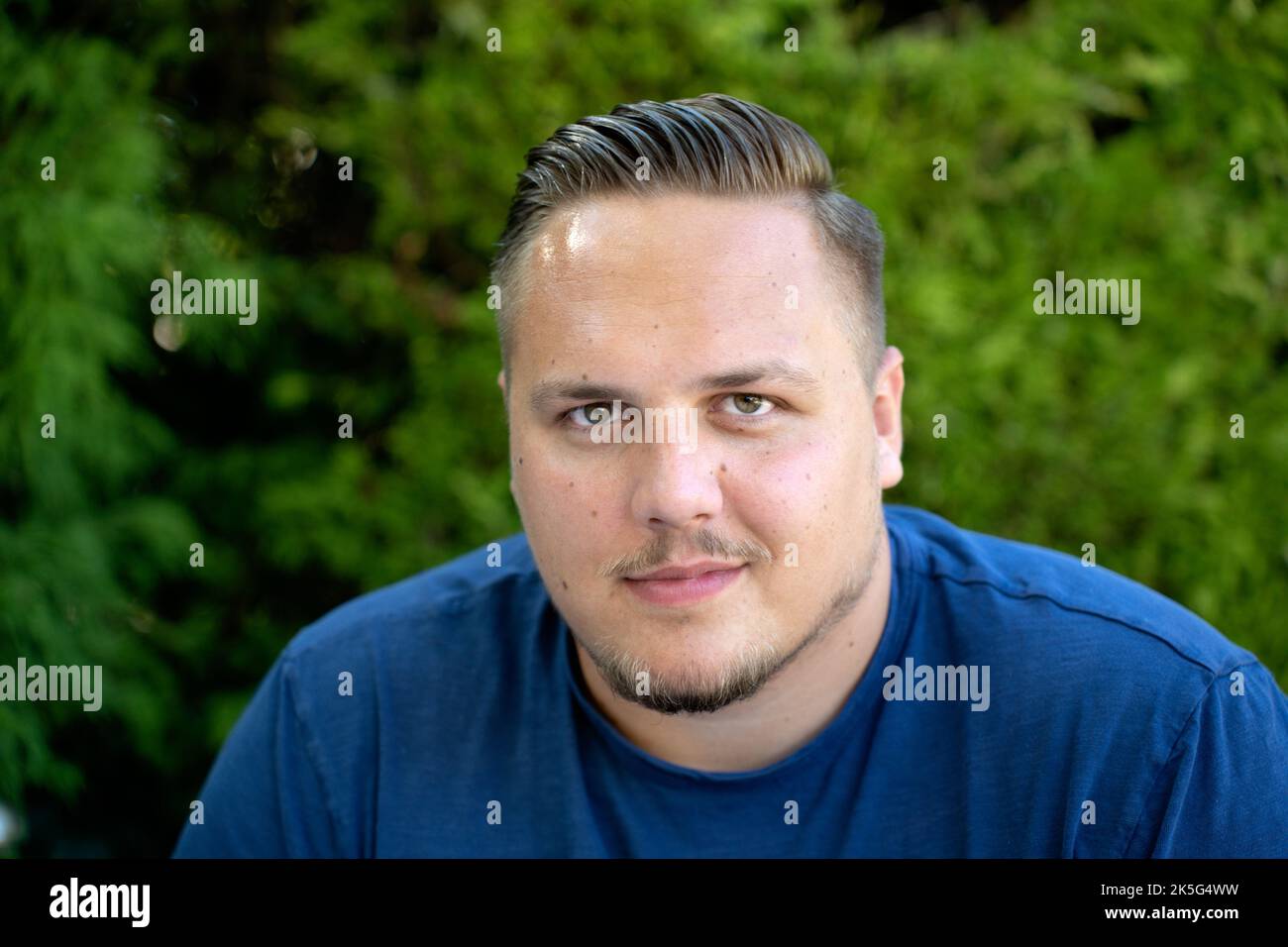 Young man looking intently at the camera with a quiet thoughtful smile ...