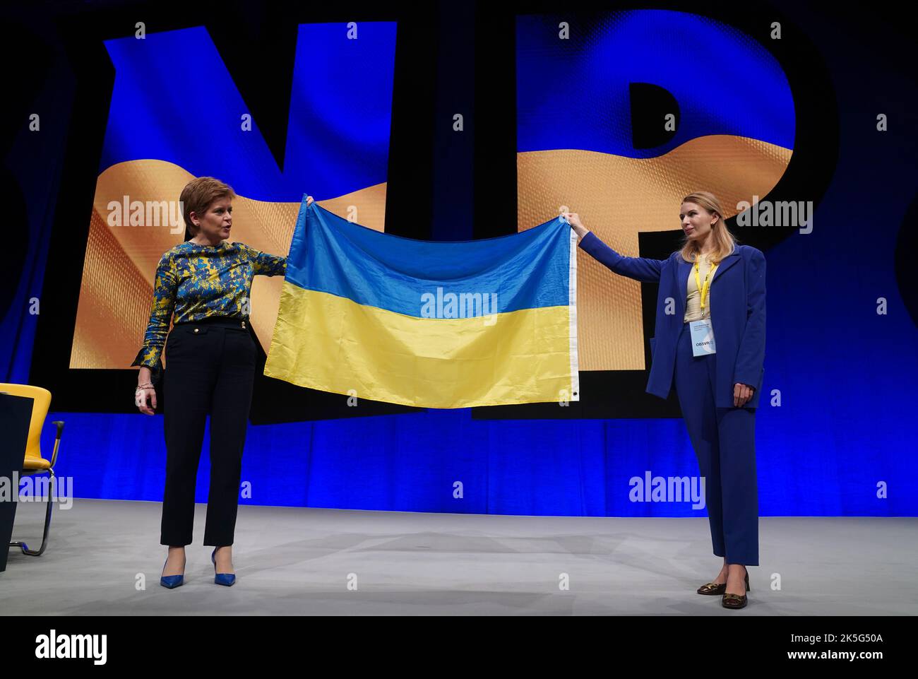 First Minister Nicola Sturgeon holds a Ukrainian flag on stage with ...