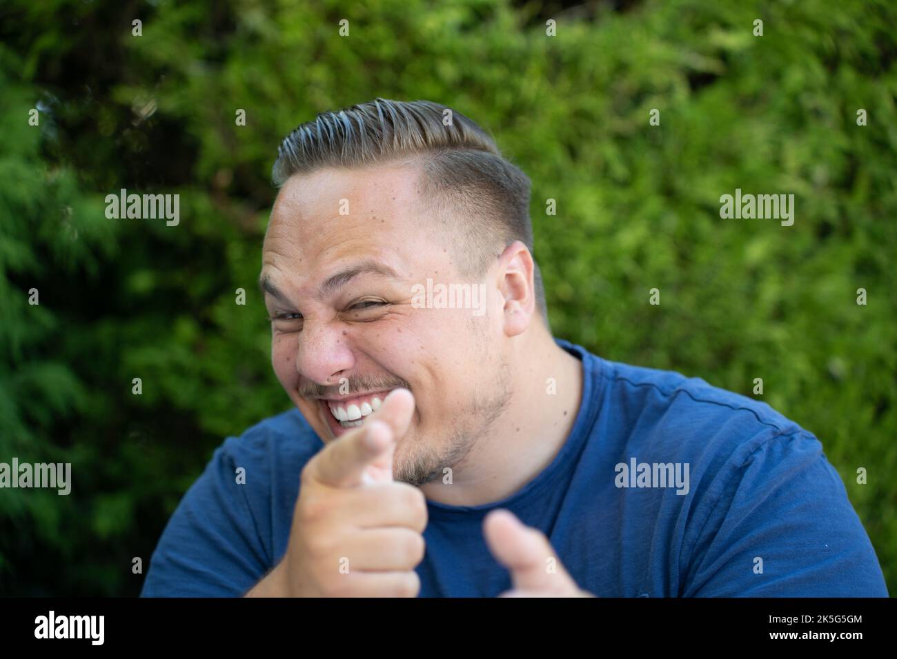 Mischievous happy young man pointing a finger at the camera with an ...