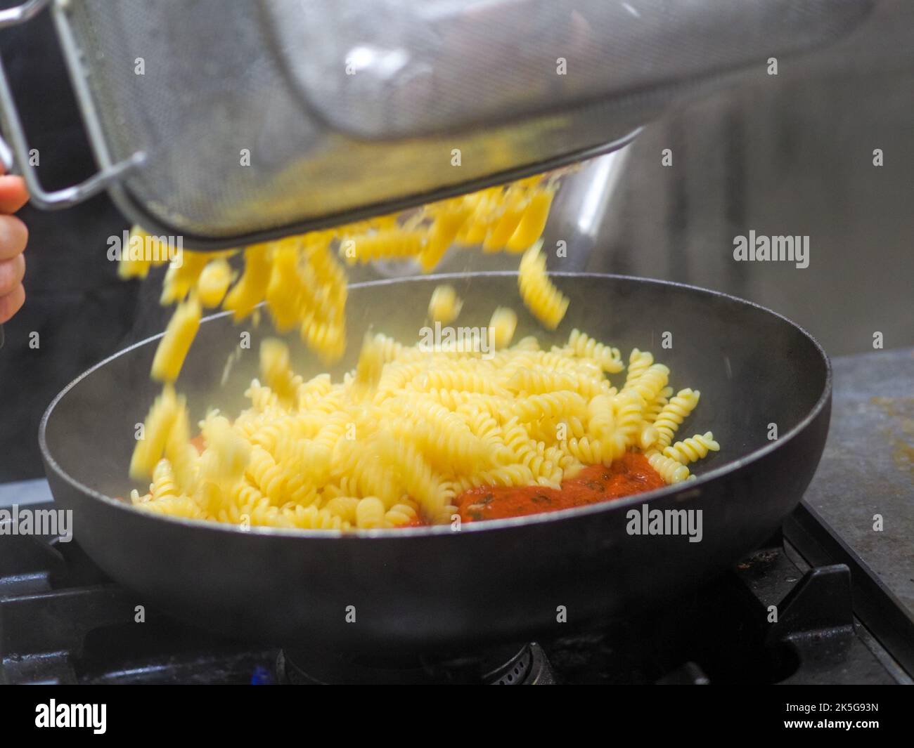 female cook tossing egg pasta in the pan Stock Photo - Alamy