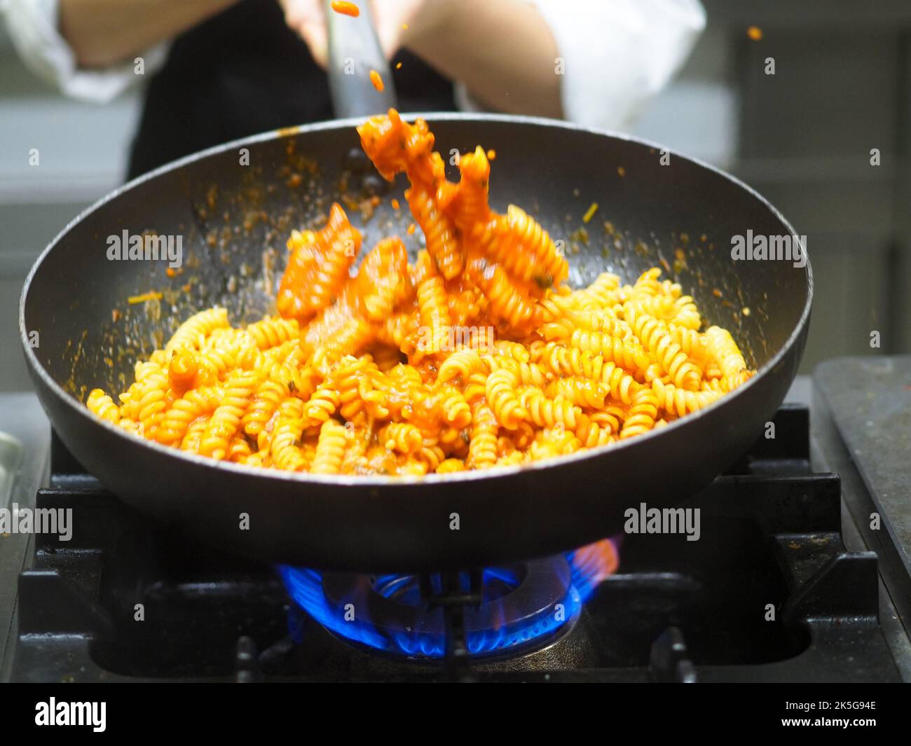 female cook tossing egg pasta in the pan Stock Photo - Alamy