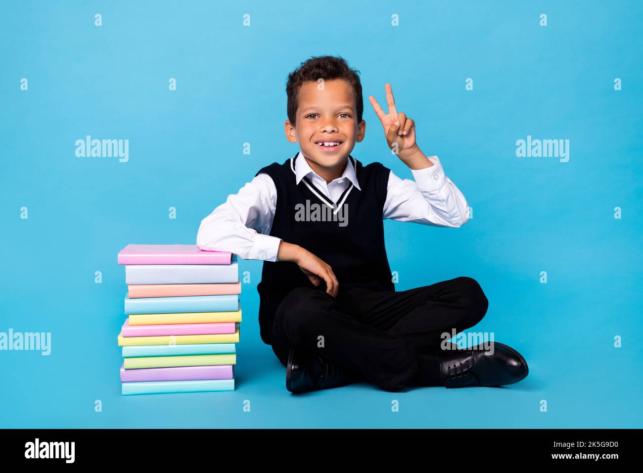 Full size photo of cheerful funny boy sit floor demonstrate v-sign ...