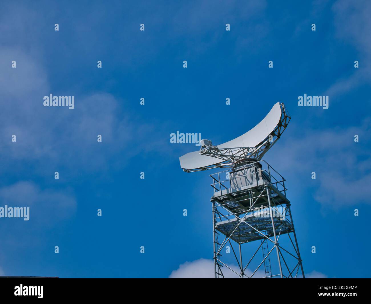 A white radar dish mounted on a steel frame tower. Taken on a sunny day ...