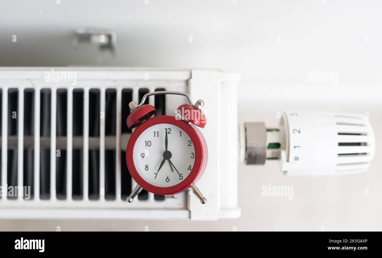 alarm clock on radiator indoors. Winter heating efficiency Stock Photo ...