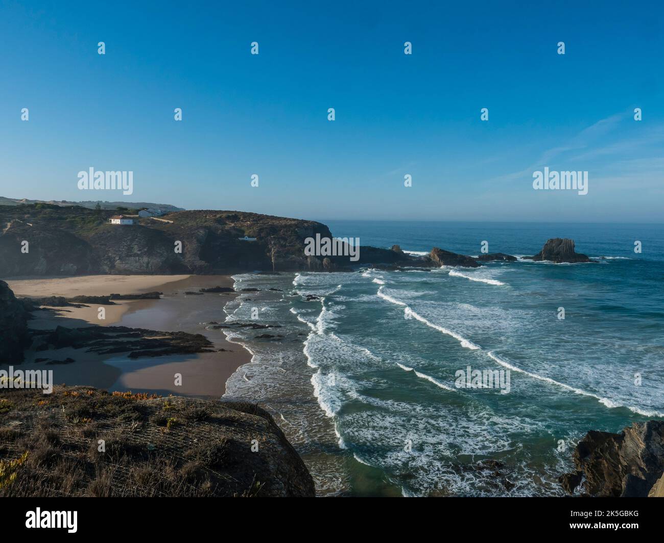 View of empty Praia da Zambujeira do Mar beach with ocean waves, cliffs ...