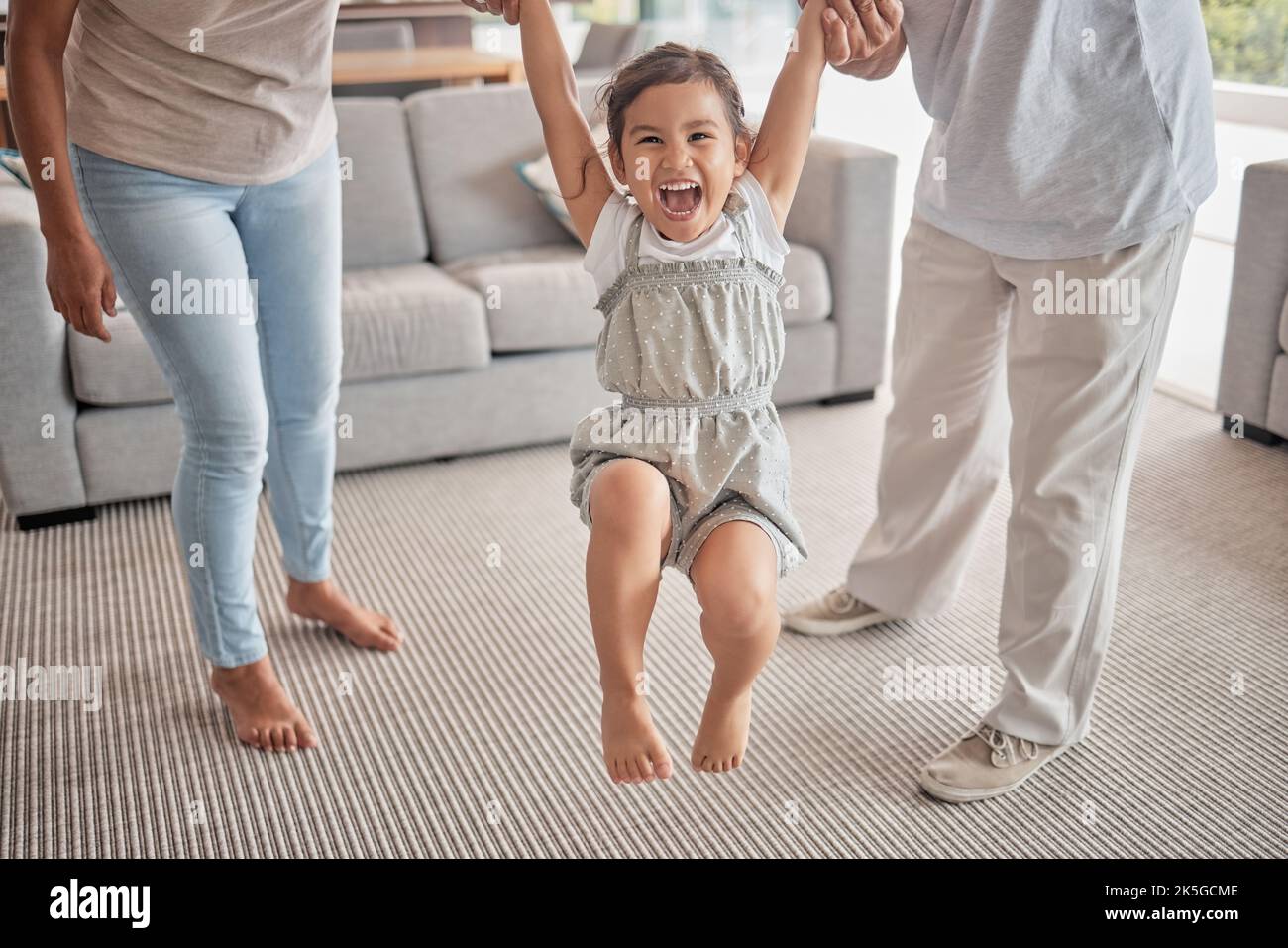 Happy child jump on carpet with grandparents holding hands for support ...