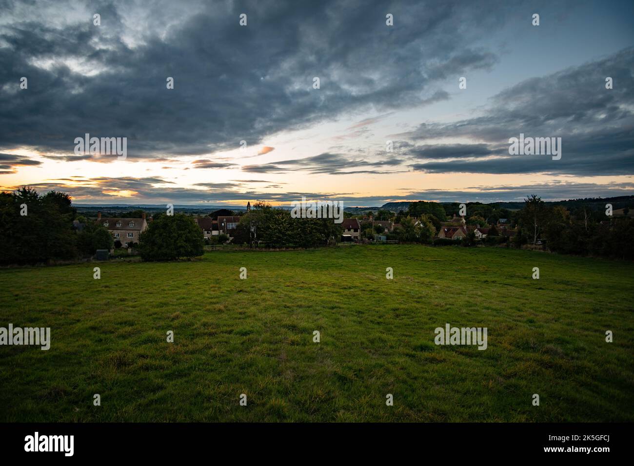 The countryside sunset with village in the background inGloucestershire ...