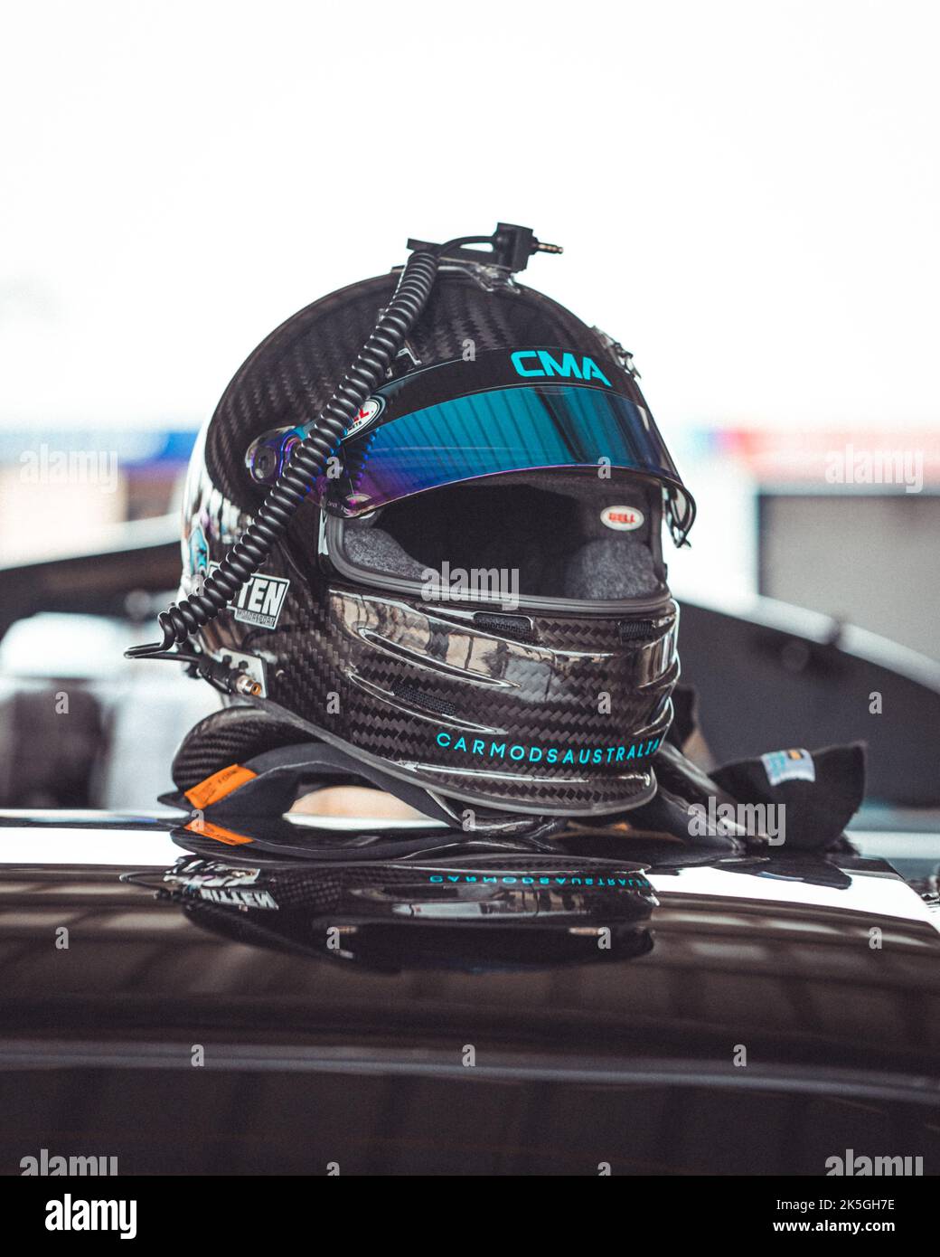 A vertical shot of a racing helmet sitting on top of a race car Stock ...