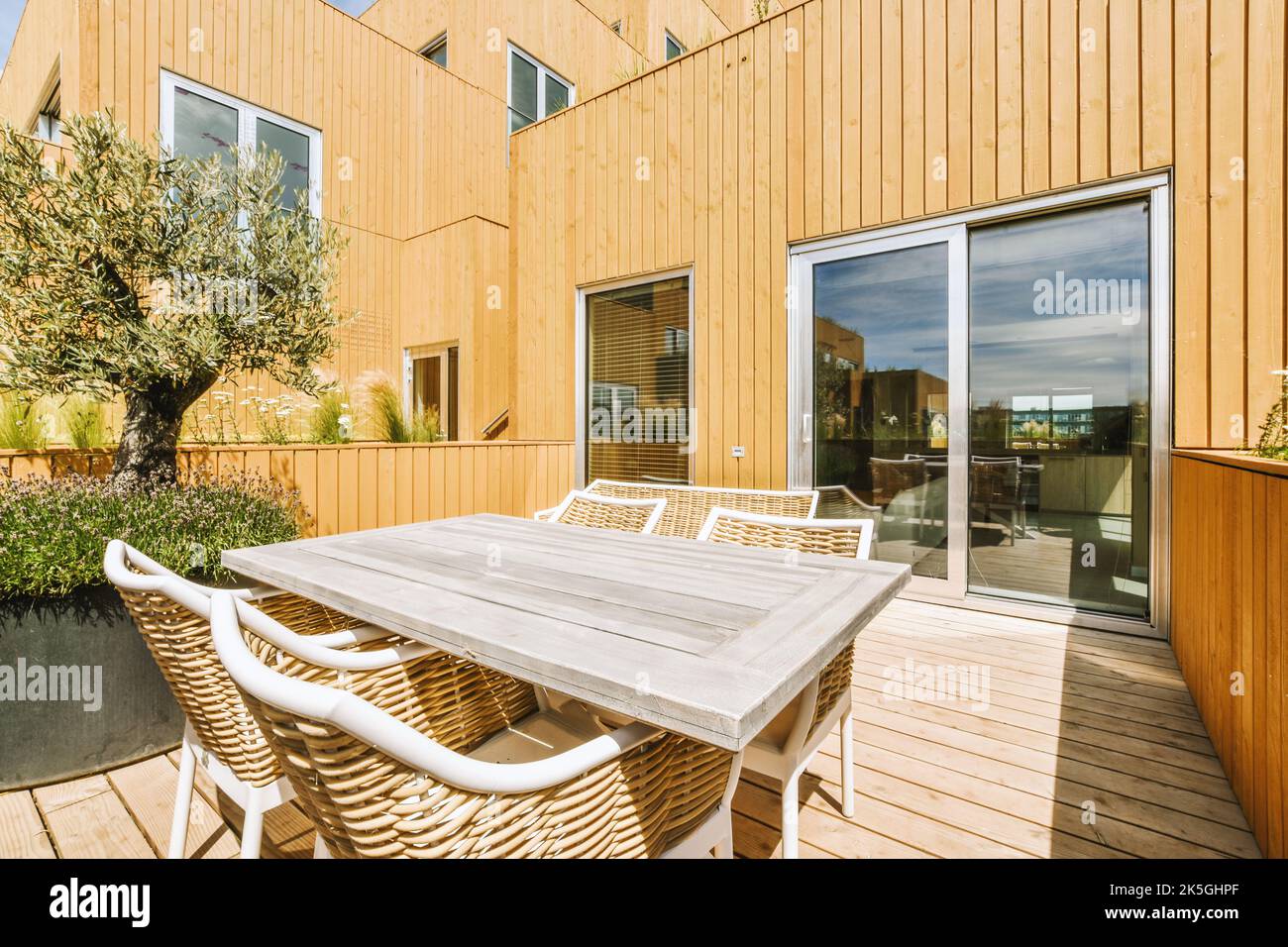 Neat paved patio with sitting area and small garden near wooden fence ...