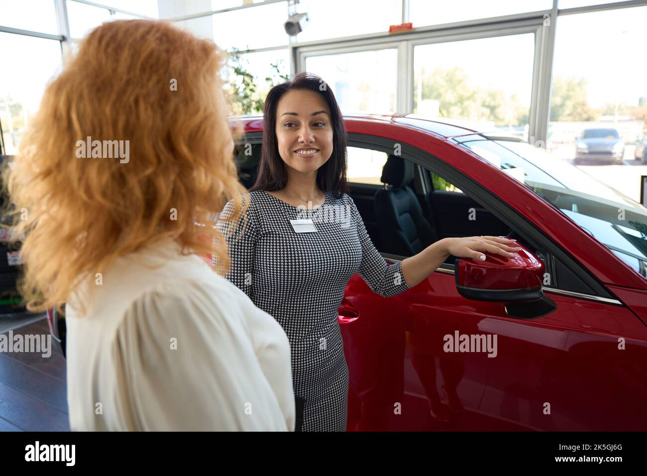 Female employee car dealership recommends car to customer Stock Photo ...