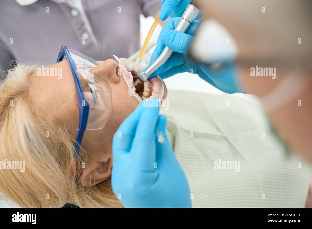 Beautiful elegant female is getting the cavity of the teeth in dental ...