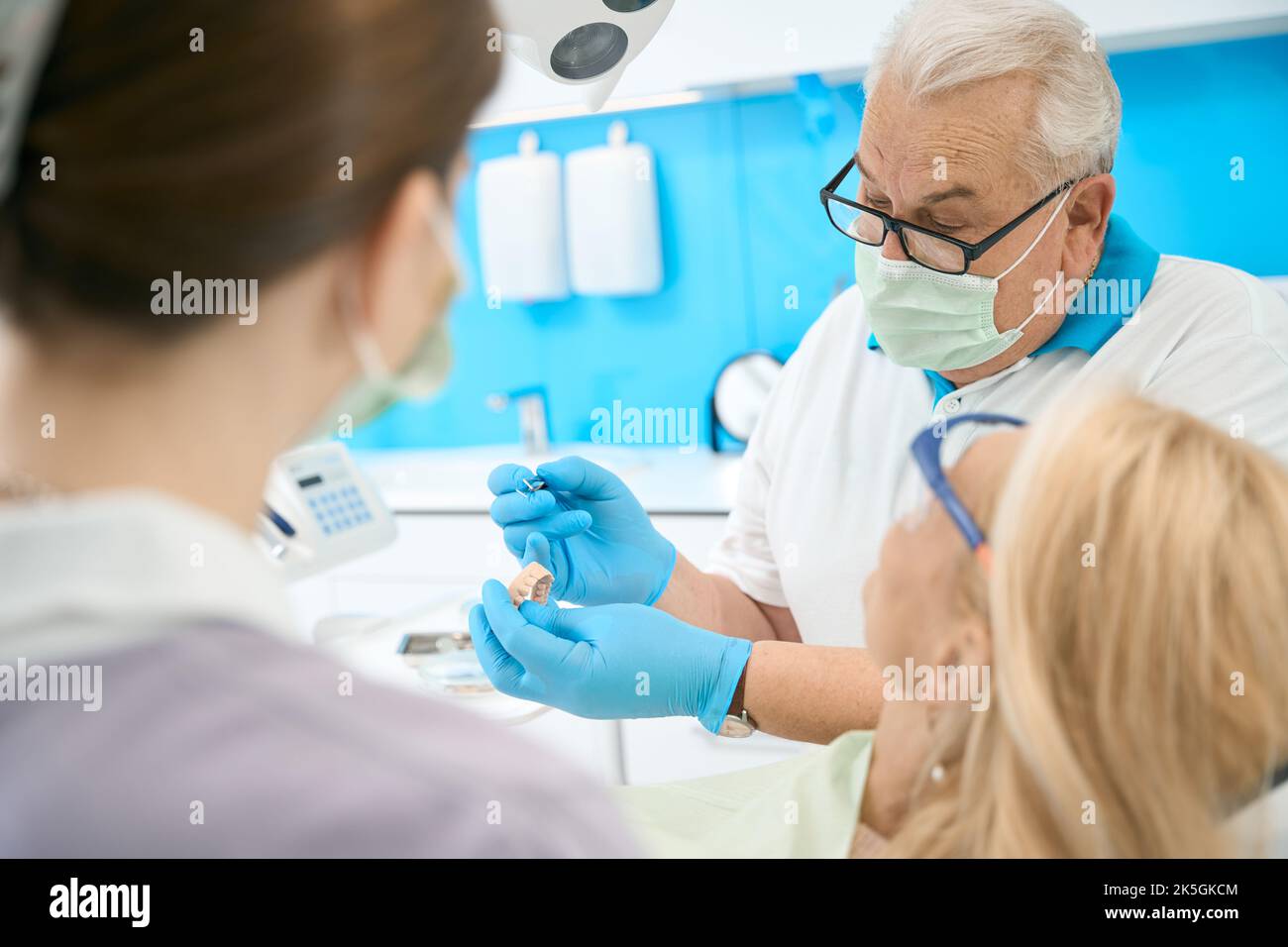 Professional orthodontist with tooth model is talking with patient ...
