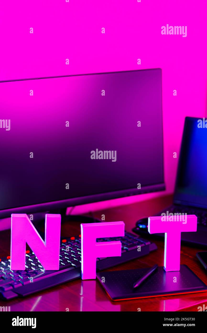 NFT inscription in pink neon light. NFT lettering at workplace with ...