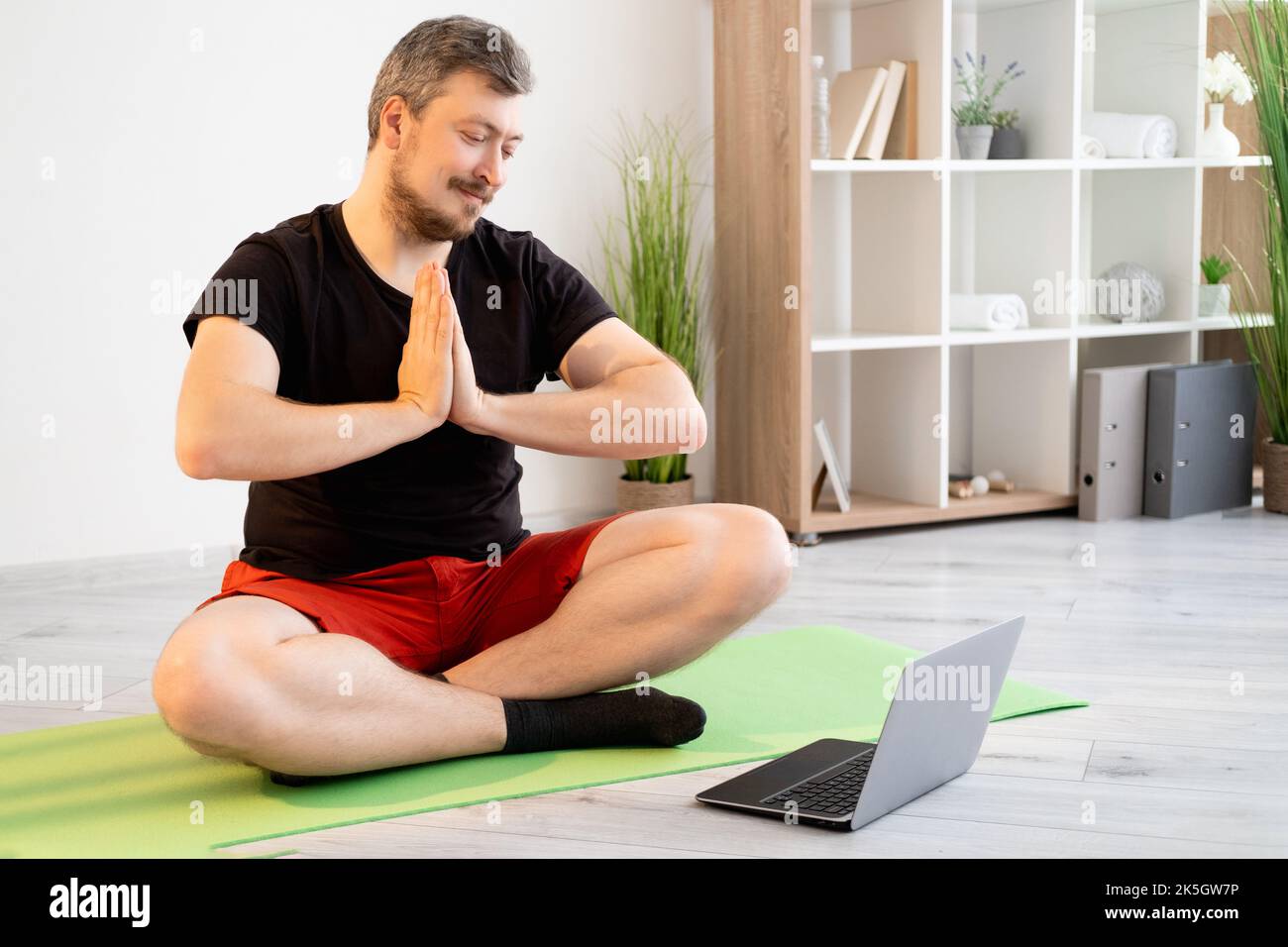 yoga practice meditating man online training Stock Photo - Alamy