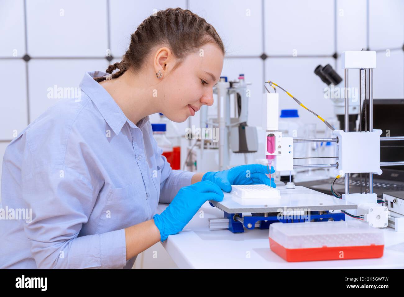 Young woman installs a microplate for DNA analysis of biological ...