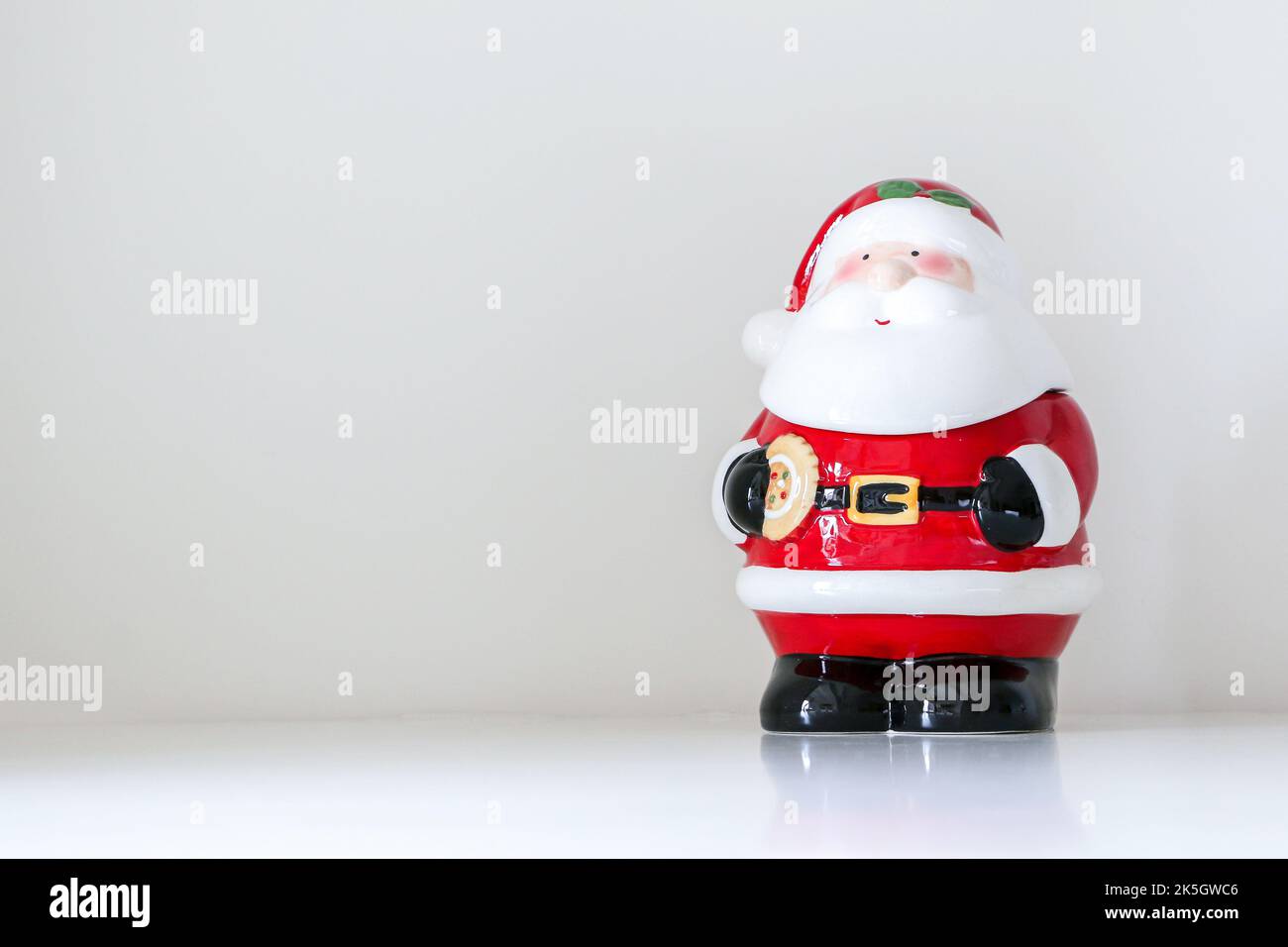 Santa Claus figurine standing slanted to the side on the right of white ...