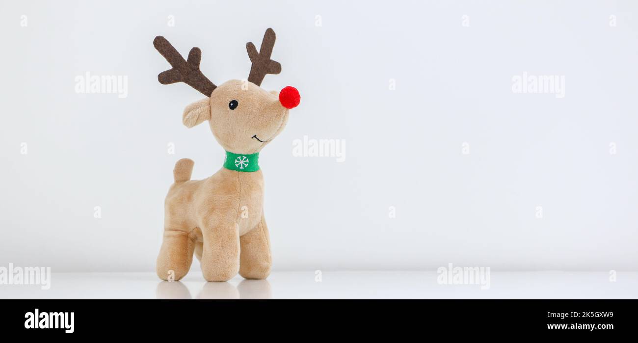 Rudolph the Red-nosed Reindeer soft toy smiling on white snowy ...