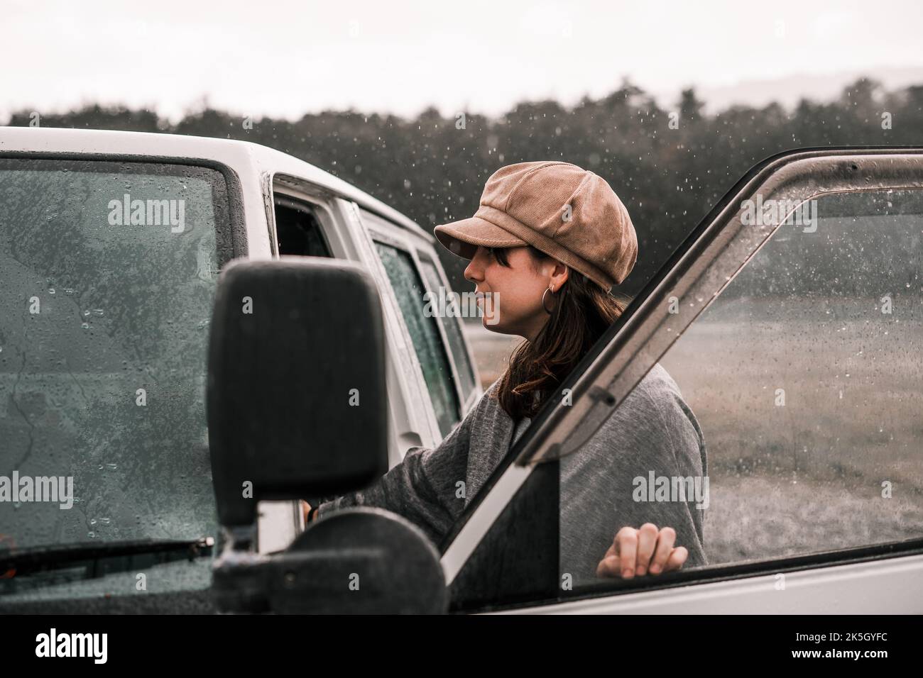 caucasian girl with gray shirt, brown cap and round earrings in her ear ...
