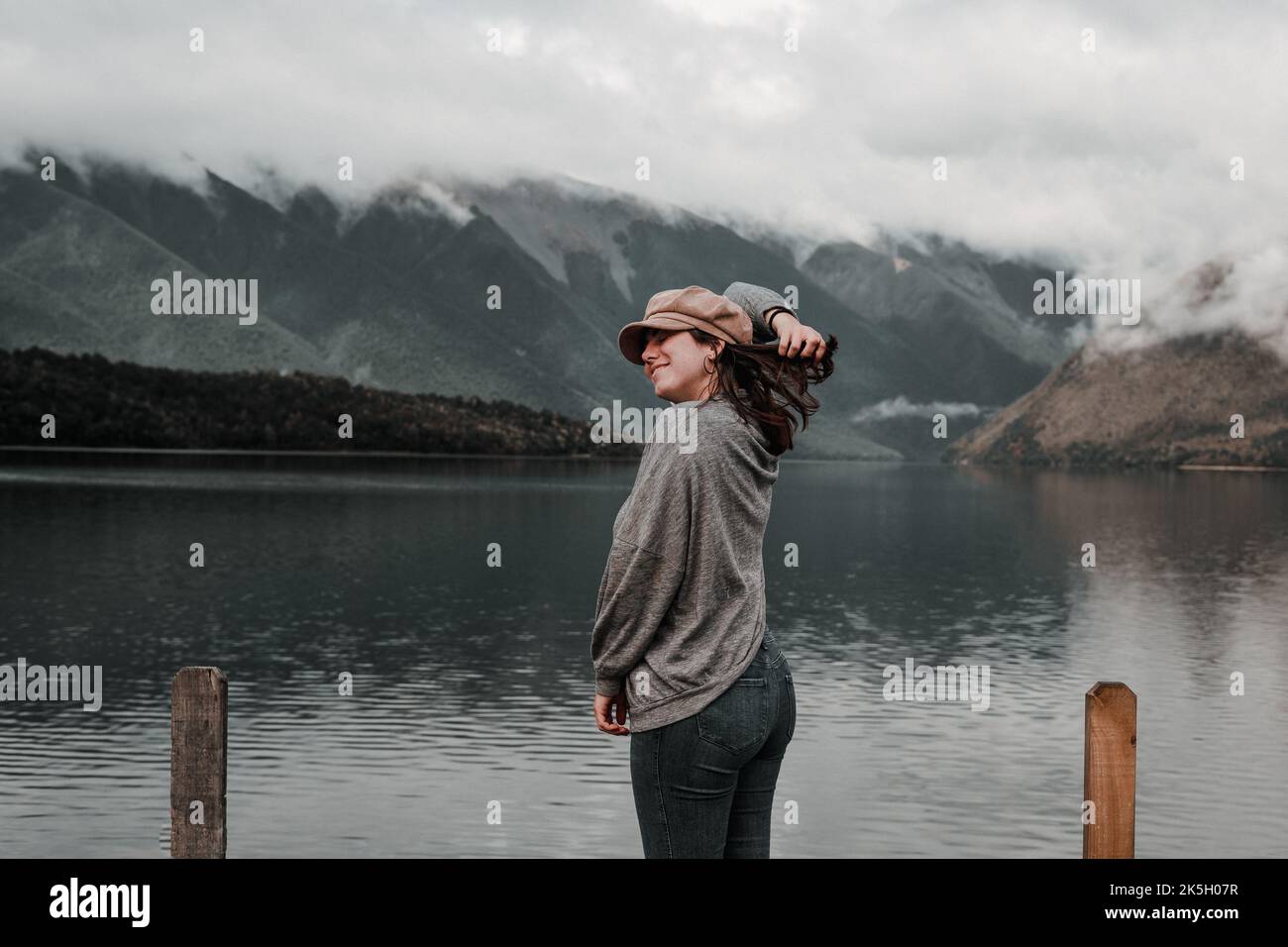 caucasian girl standing at the end of the jetty smiling happily with a ...
