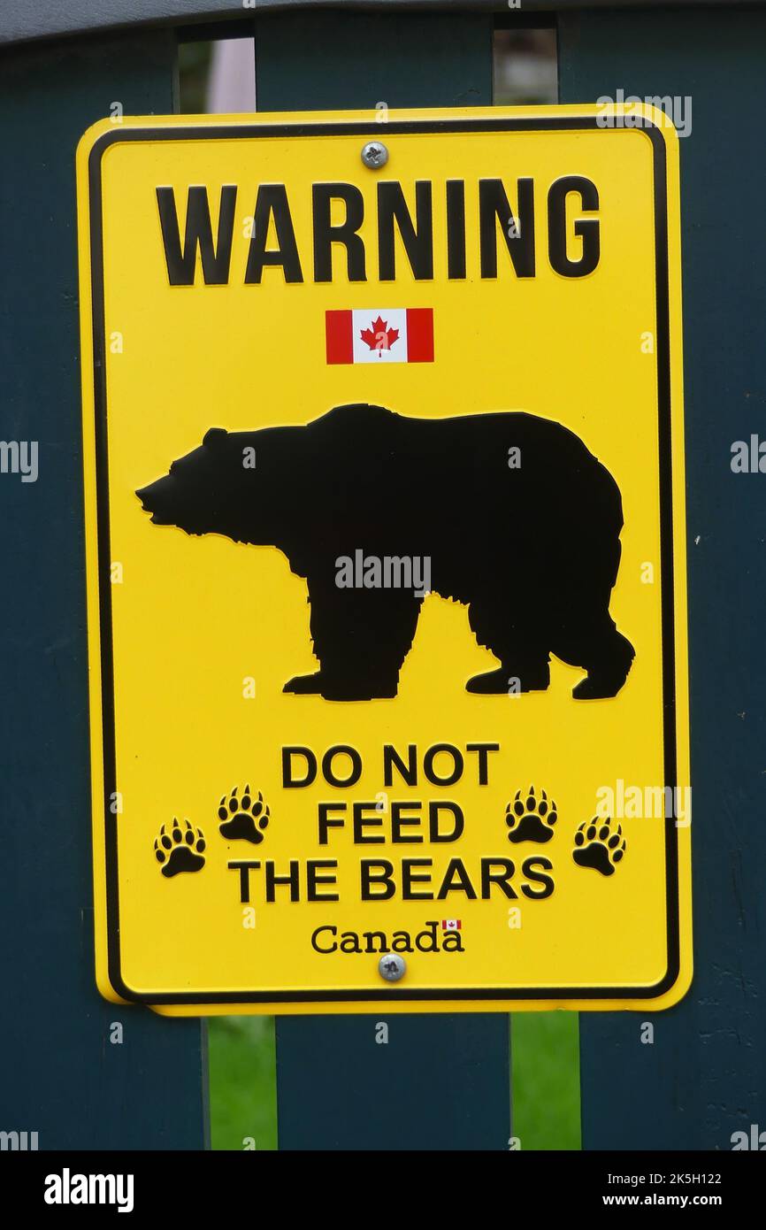 A yellow sign warning about not feeding bears Stock Photo - Alamy