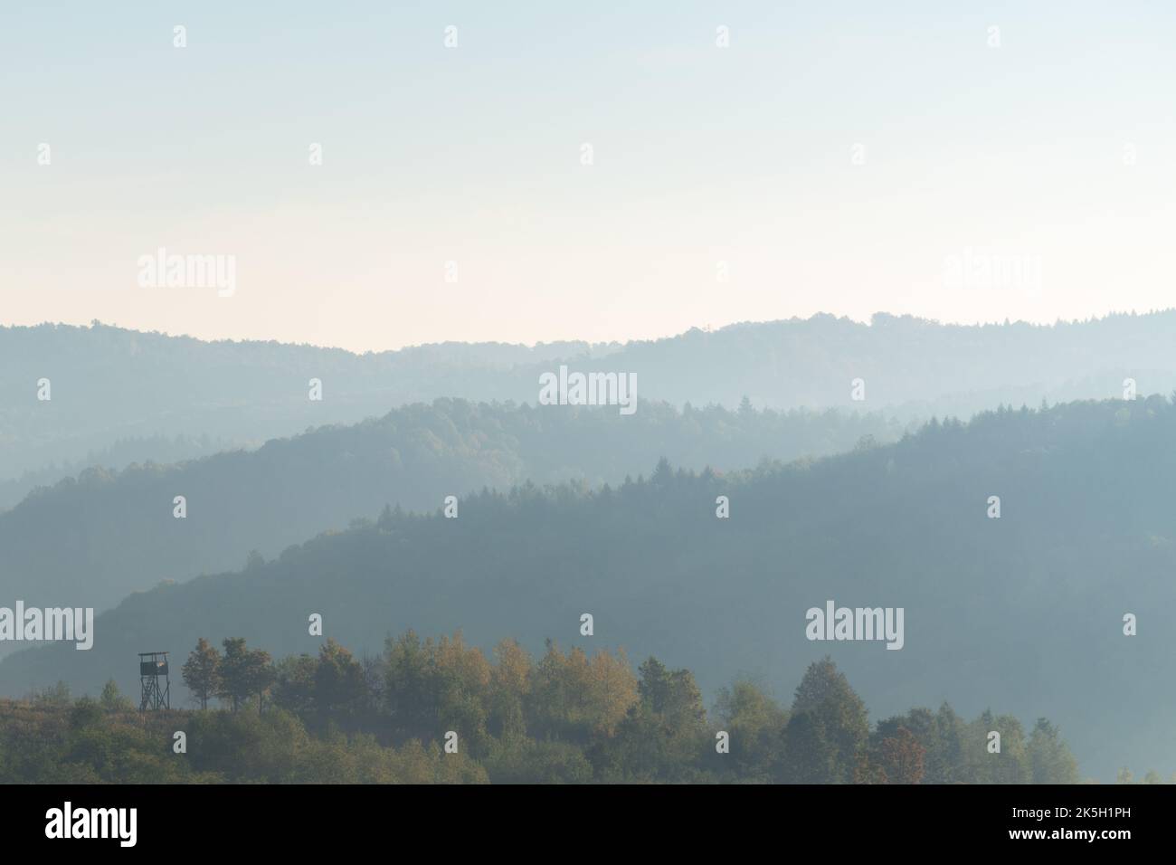 Hunter lookout tower on hill against hill layers in mist, autumn season ...