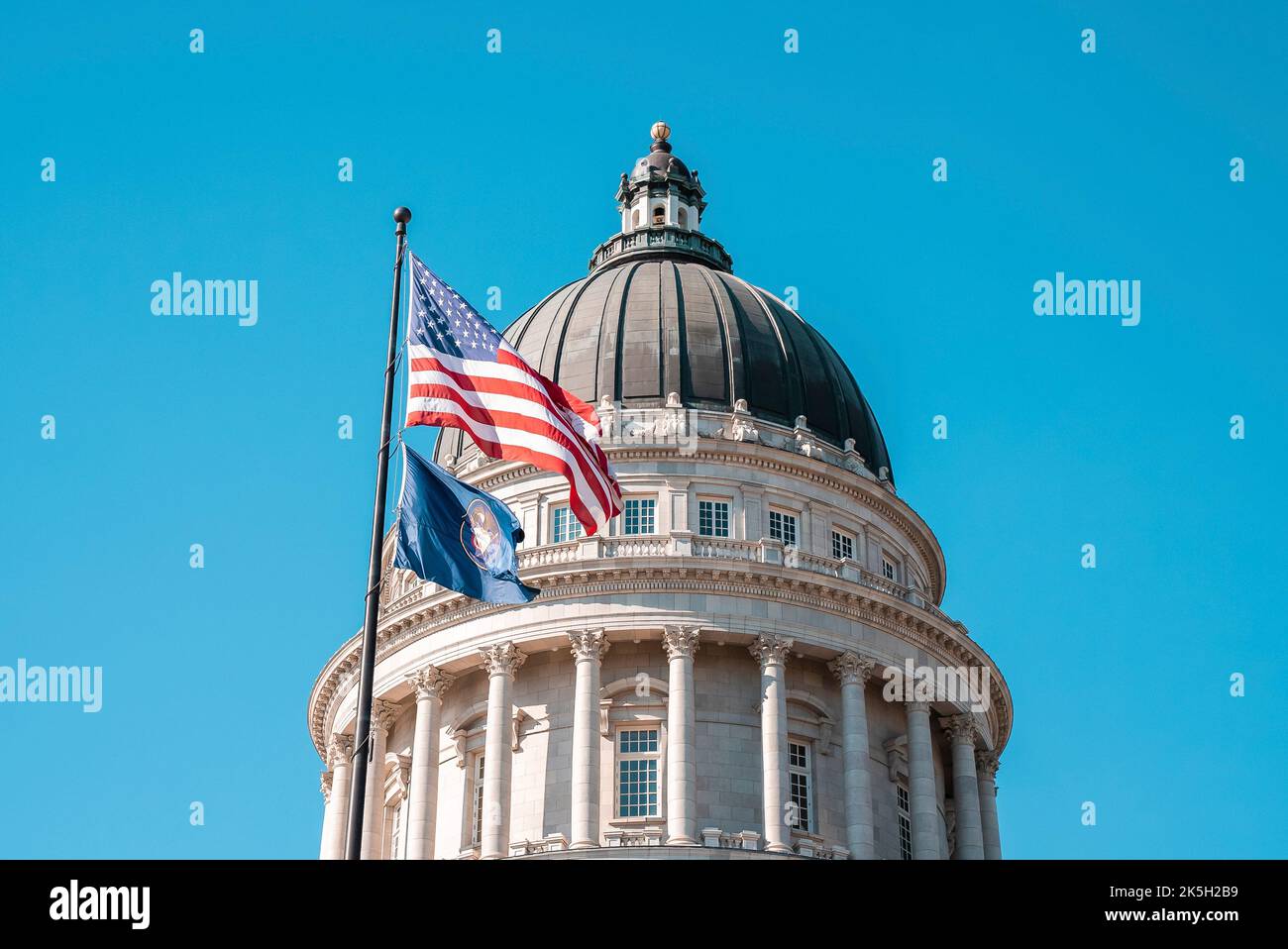 American flag waving at State Capitol Building with blue sky in ...