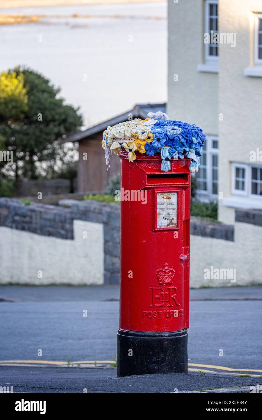 Traditional red post box with multi coloured embroidery hat on top in ...