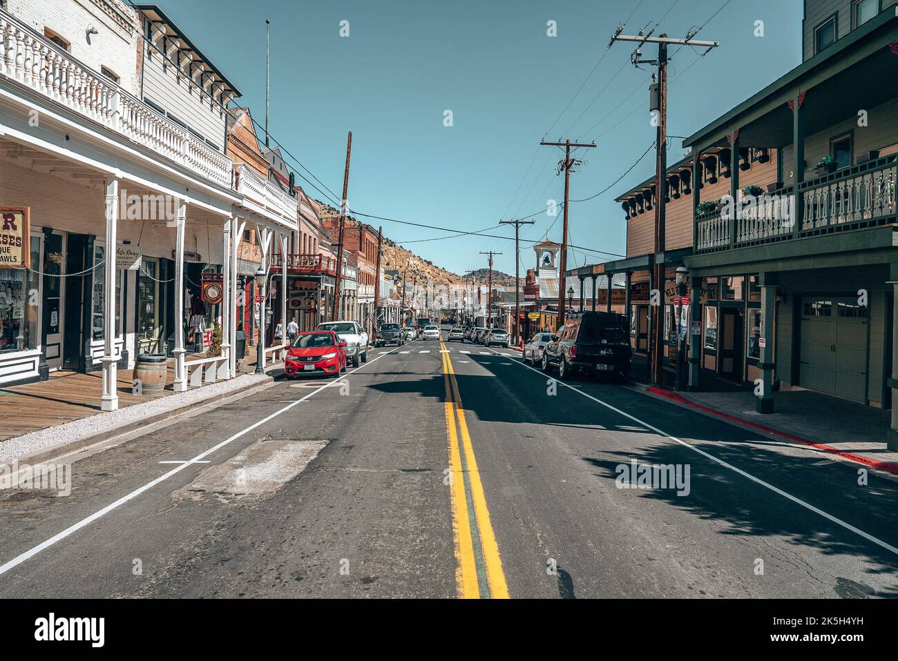 Cars parked on roadside amidst shops at historic city on sunny day ...