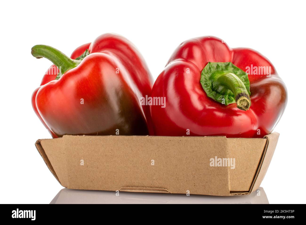 Two sweet peppers in a paper box, close-up, isolated on a white ...