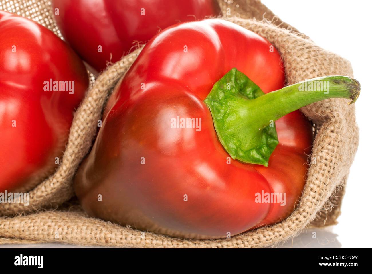 Three red organic, bell peppers in a jute bag, close-up, isolated on ...