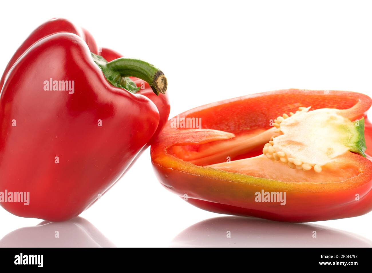 One whole and one half of a red bell pepper, close-up, isolated on ...