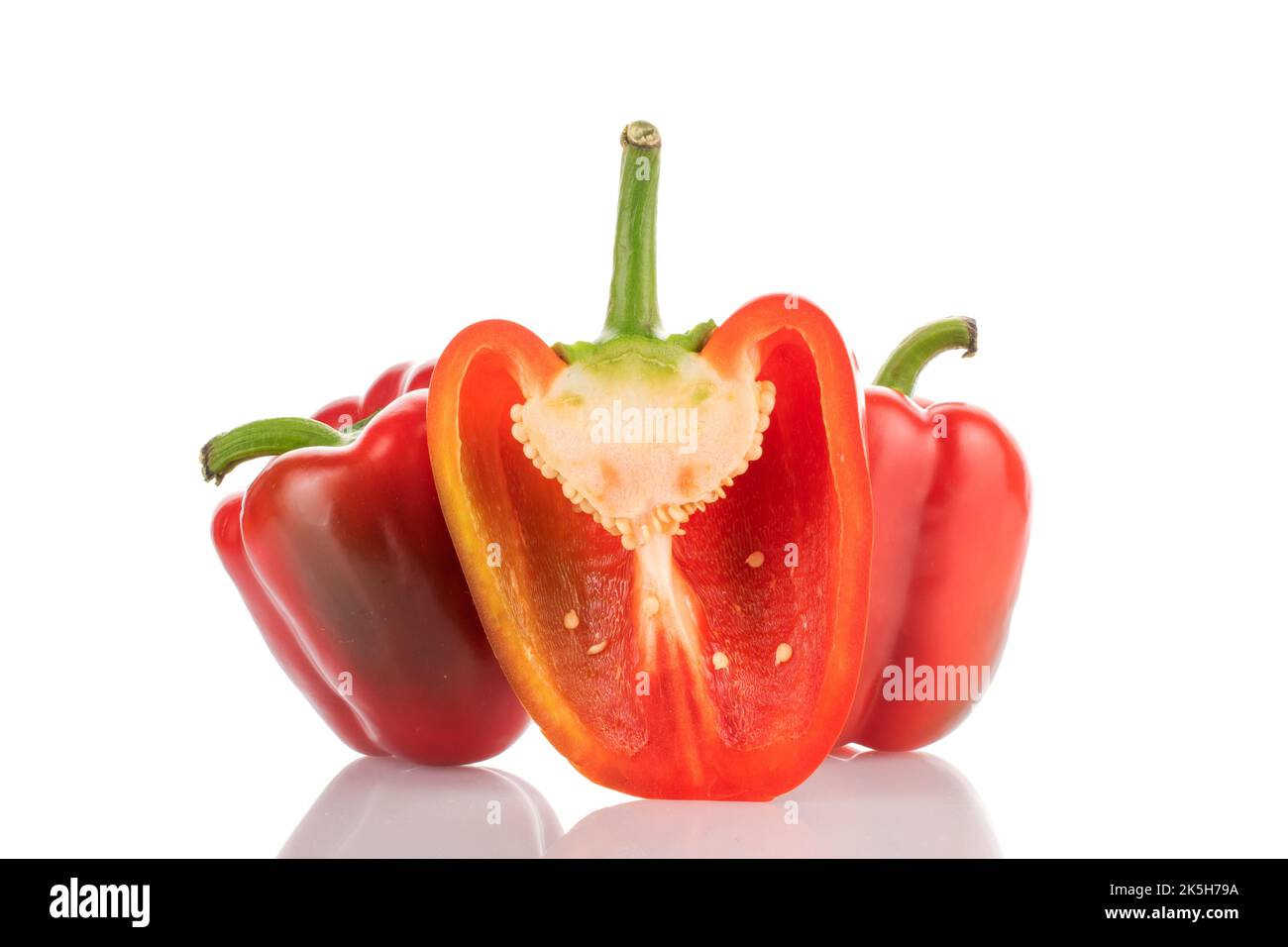 One half in the foreground and two whole, red bell peppers in the ...