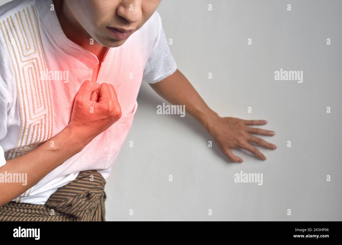 Asian young man suffering from central chest pain. Chest pain can be ...