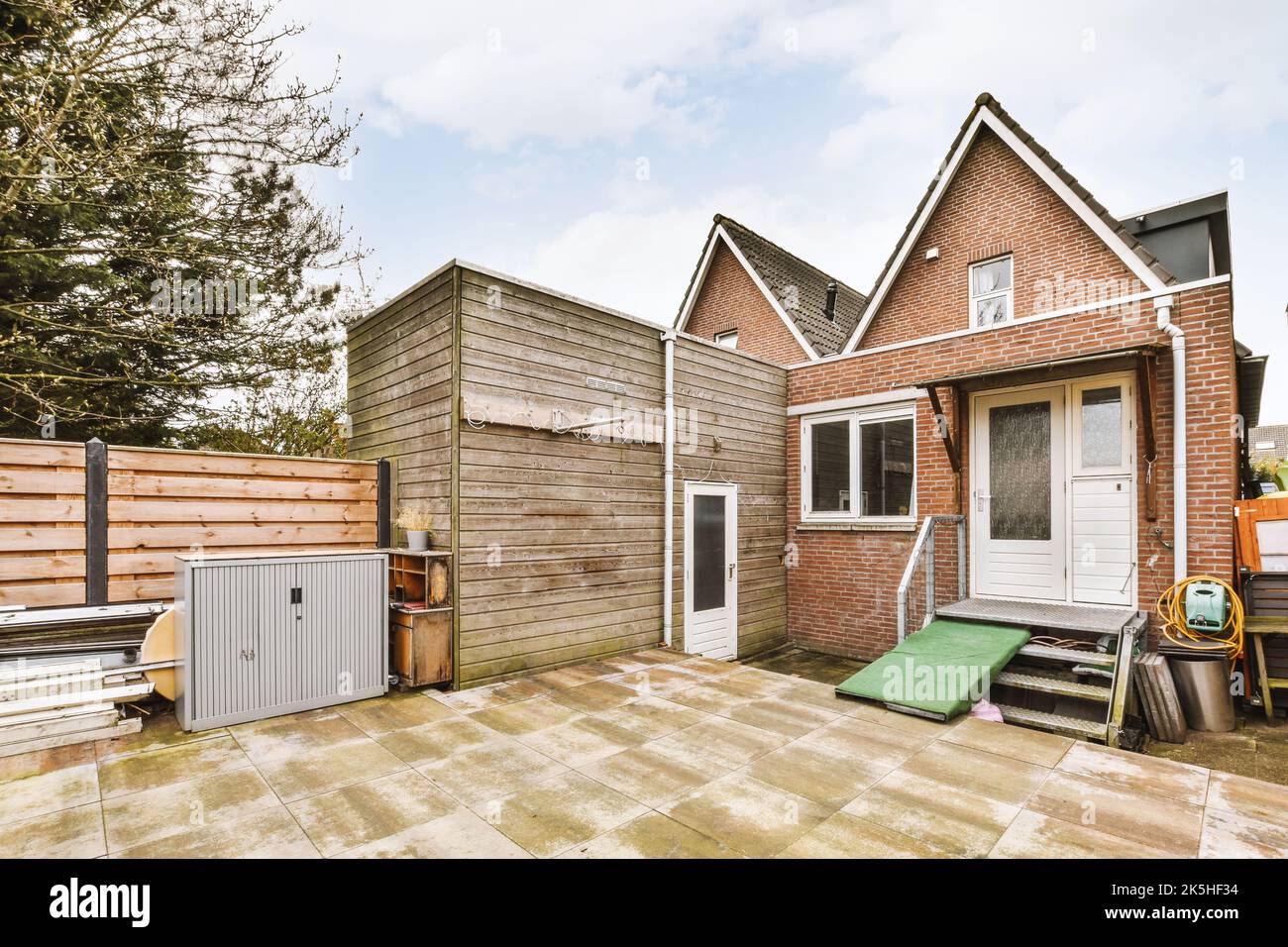 Spacious garage with closed white door and wooden walls with hangers on ...