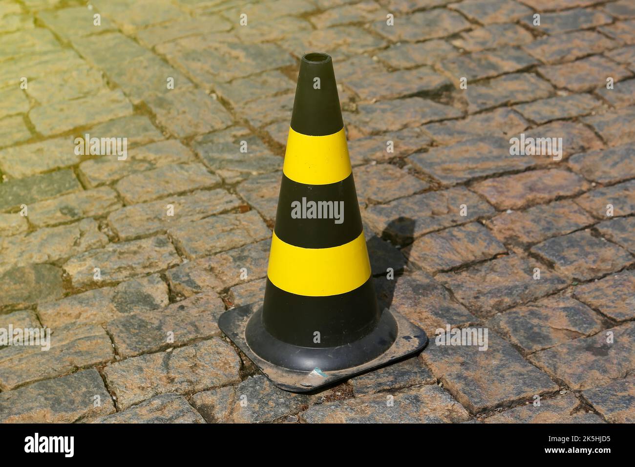 traffic signal cone yellow and black colors, hard plastic, on stone ...