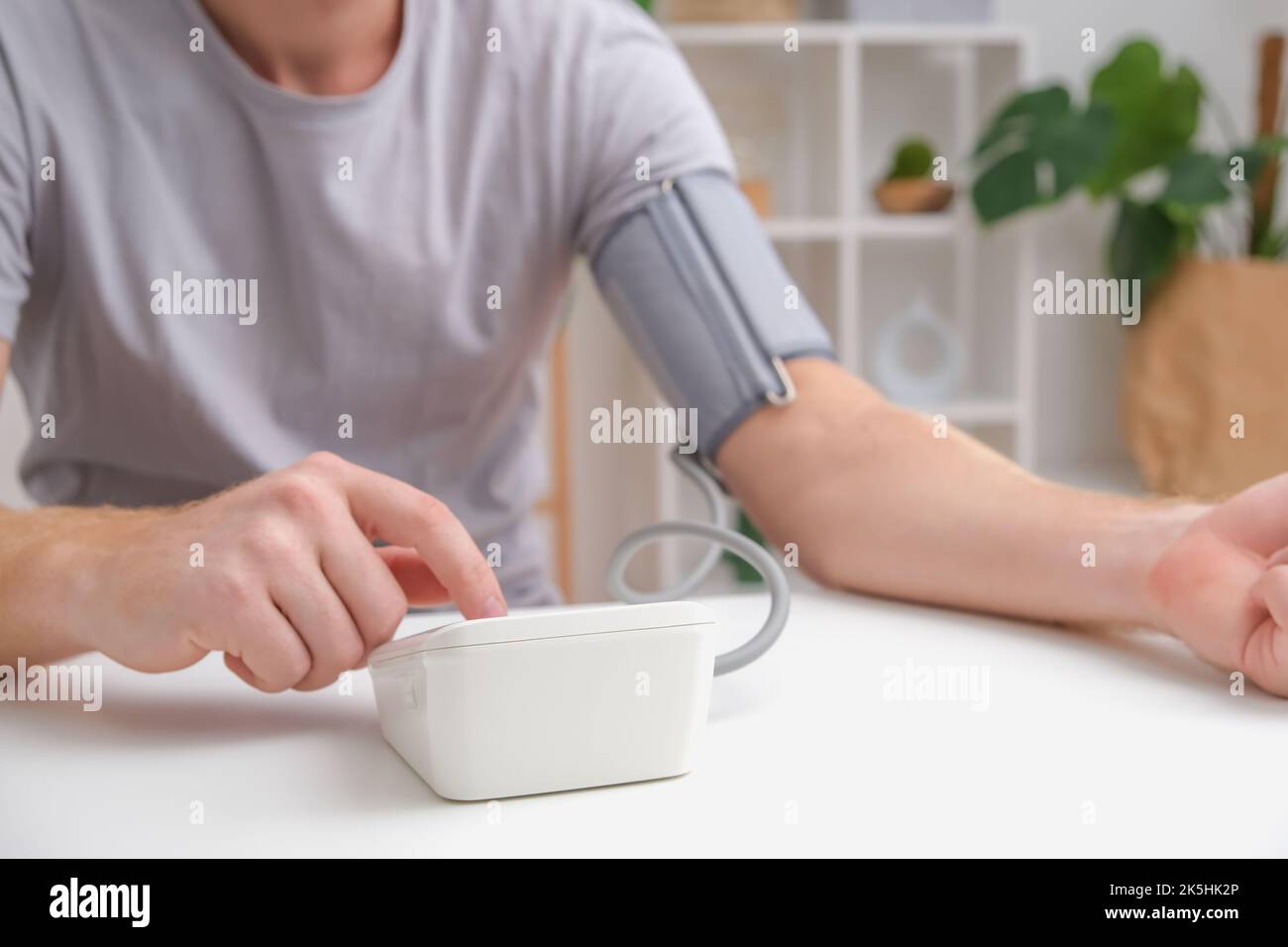 A man measures blood pressure with a white electric tonometer lying on ...