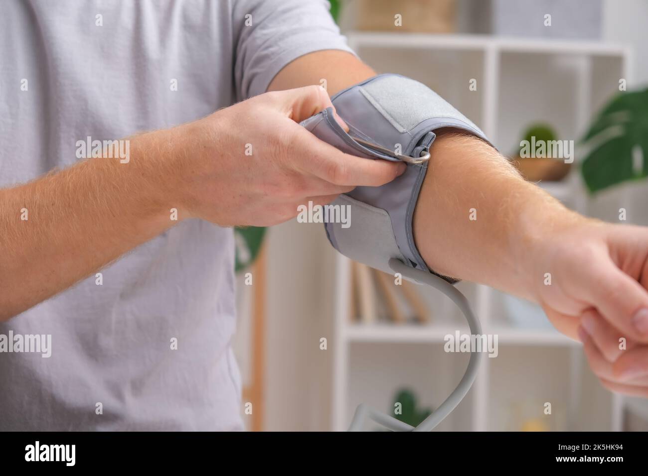 A man measures blood pressure with a white electric tonometer lying on ...