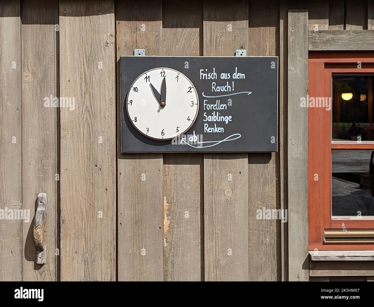 A wooden door with adjustable clocks hands and sign "fresh from the ...