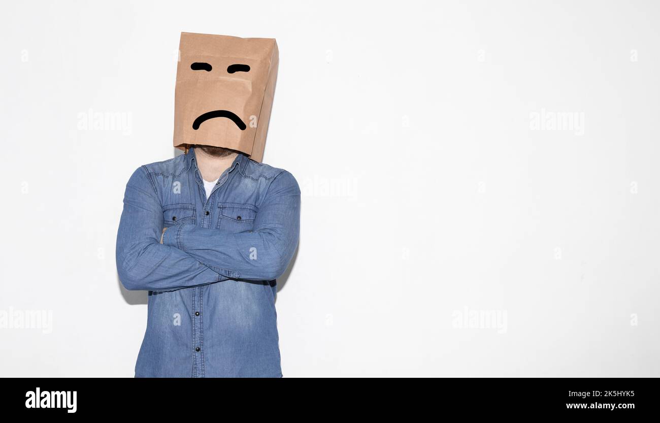 A man wearing a brown paper bag over his head with a sad face ...